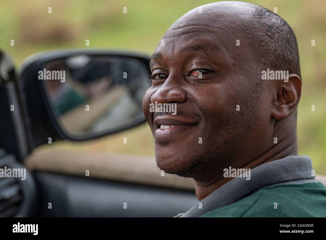 Portrait of a smiling Rwandan man in a safari vehicle operated by ...