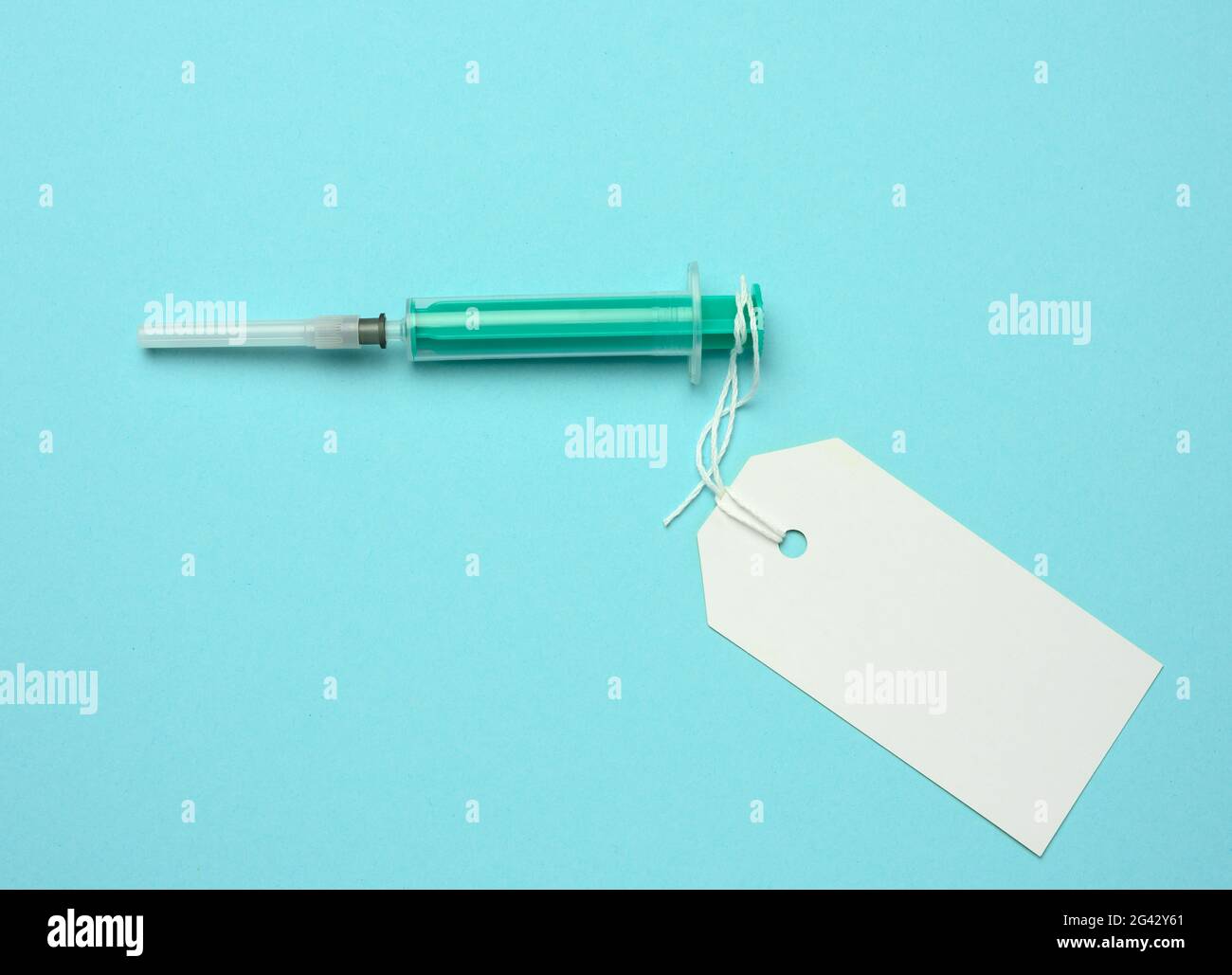 Plastic syringe and attached white paper tag on blue background Stock ...