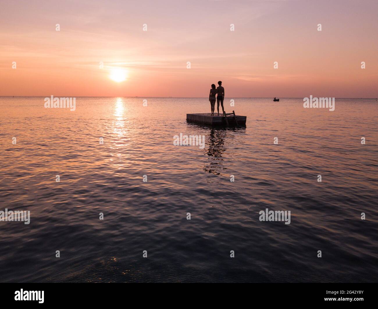 Aerial view silhouette of young couple standing on a bathing platform ...