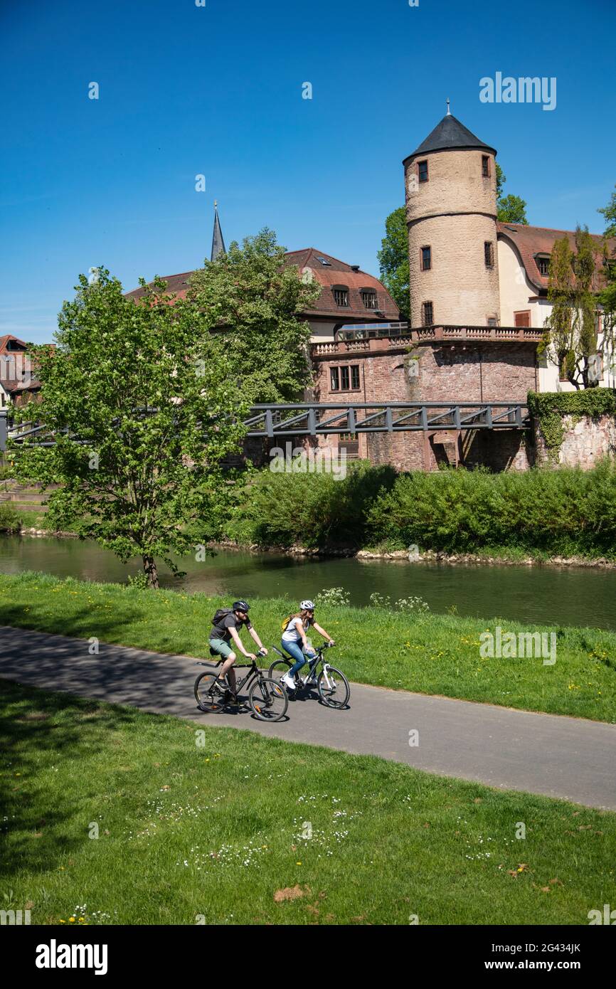 Cyclists on cycle path along the Tauber with the former Princely Court ...