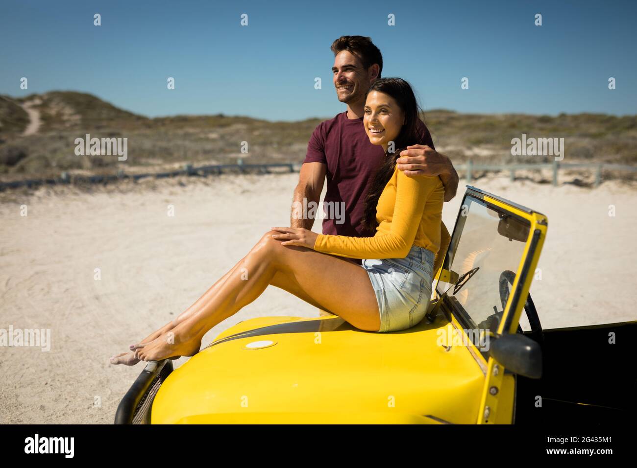 Happy Caucasian Couple Man Embracing Woman Sitting On Beach Buggy By