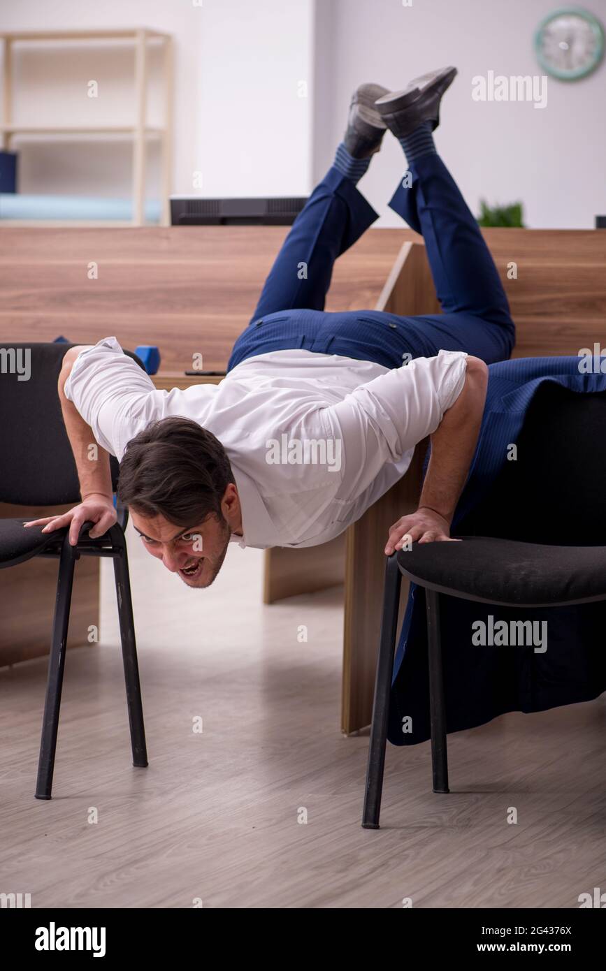 Young businessman employee doing sport exercises at workplace Stock ...