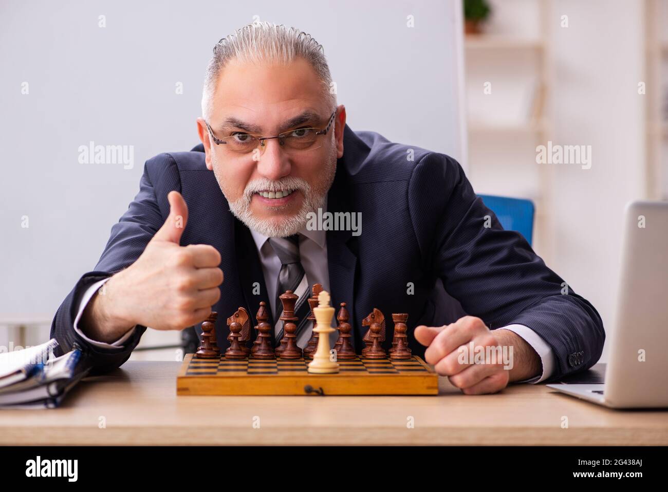 Old male employee playing chess at workplace Stock Photo - Alamy
