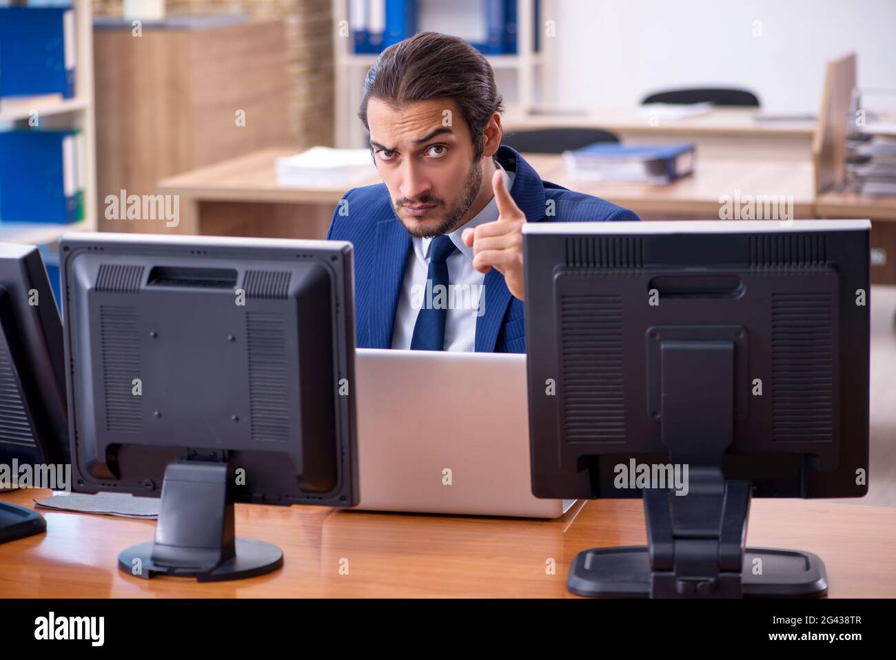 Young male employee in multitasking concept Stock Photo - Alamy