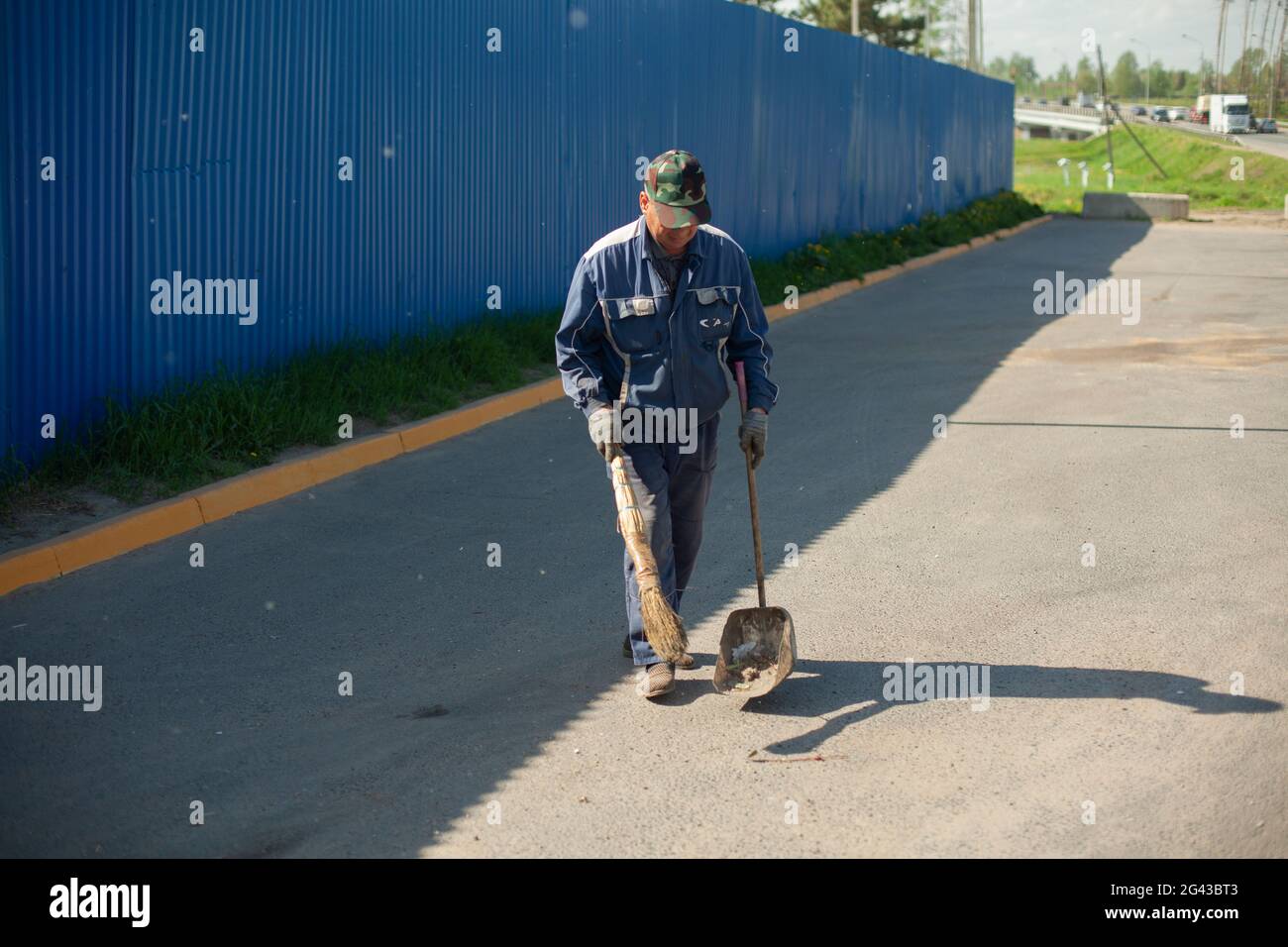 Road cleaner. The janitor sweeps the area with a broom. Removing ...