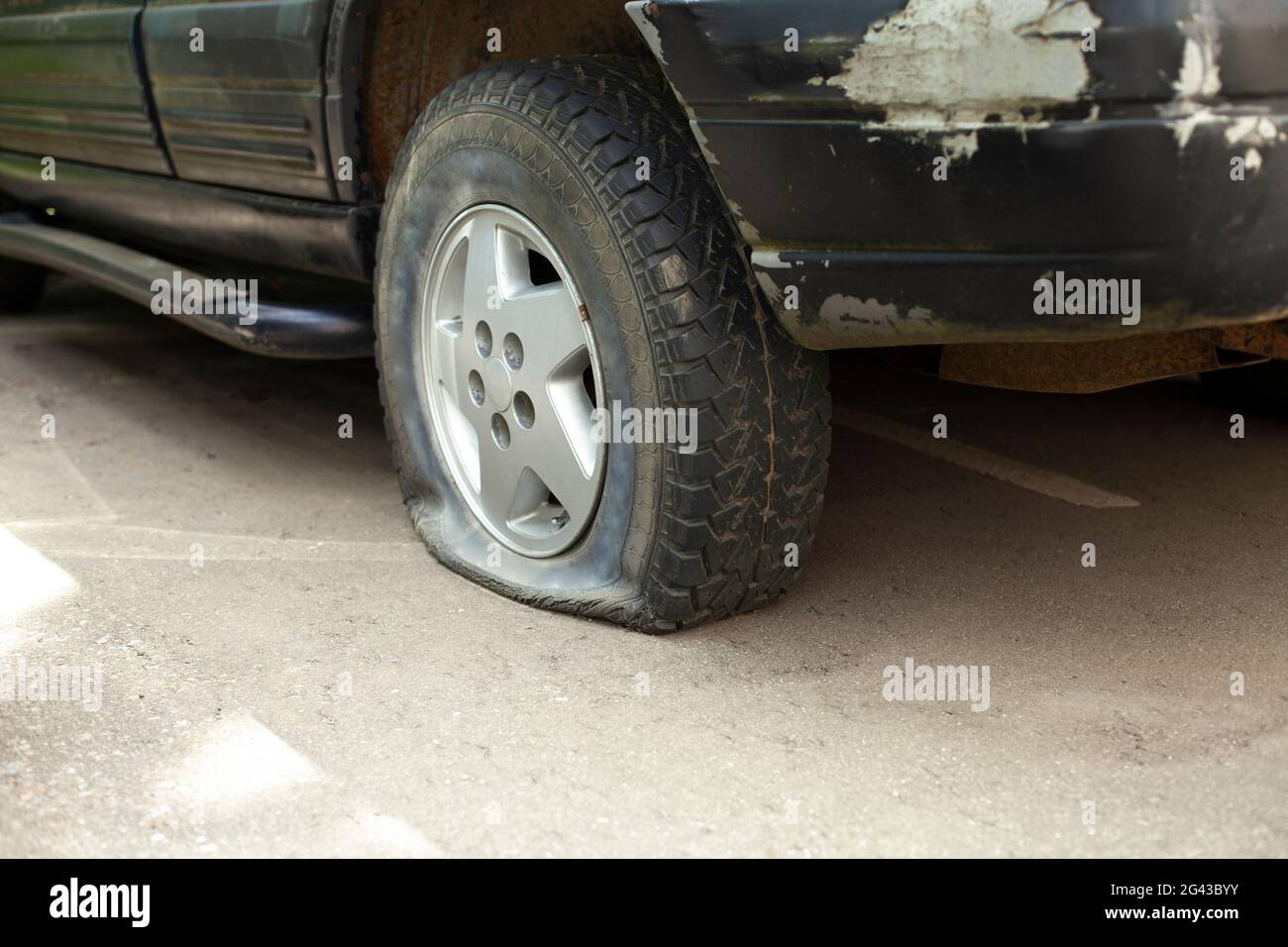 A deflated car wheel. Punctured tire on the car. Damaged transport. The ...