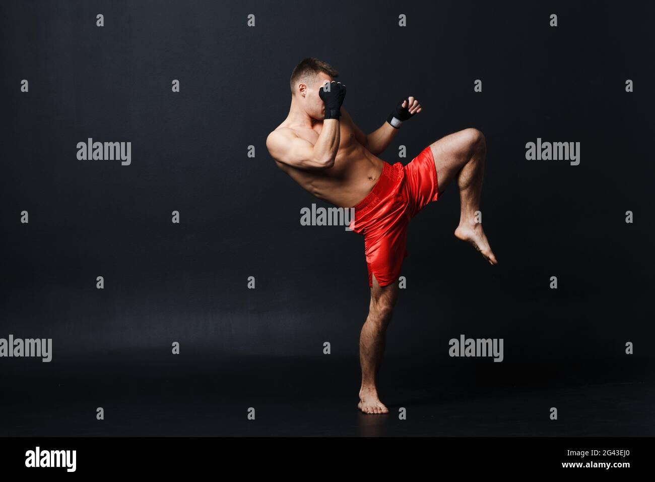 Sportsman muay thai man boxer stance ad knee kick at black background ...