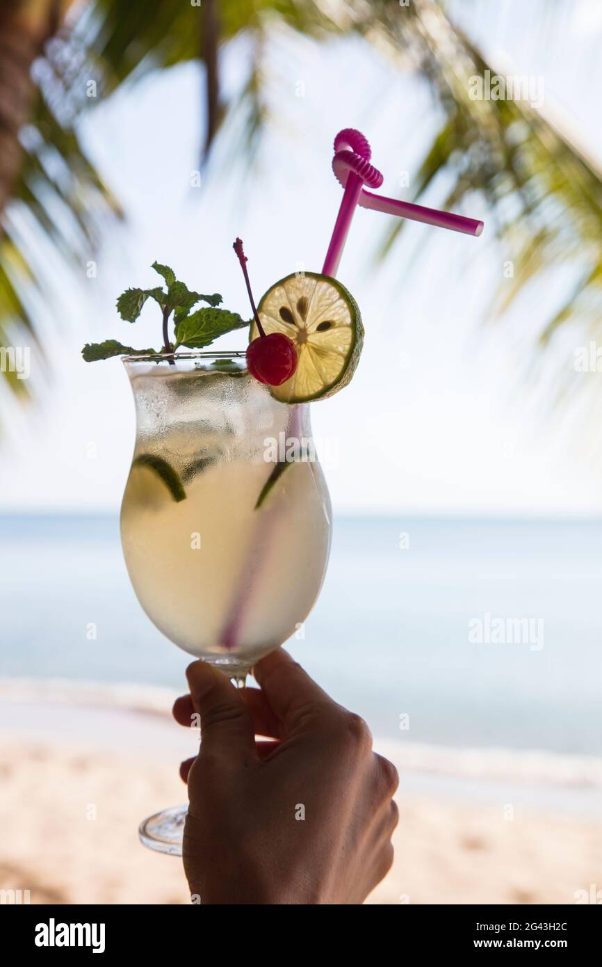 Hand holds cocktail glass with fresh lime juice in the restaurant and ...