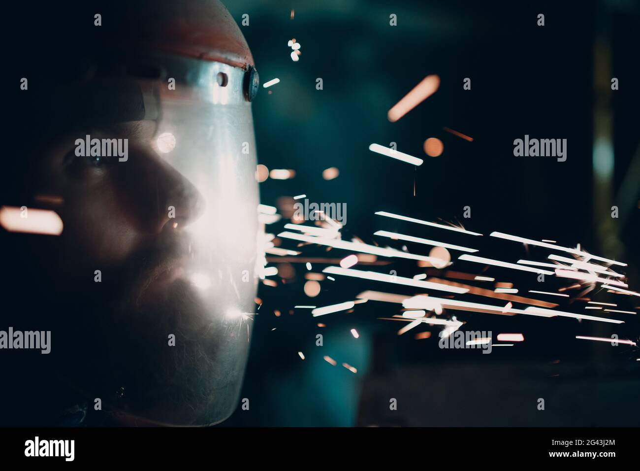Man welder grinder in transparent protective mask with flying sparks in ...