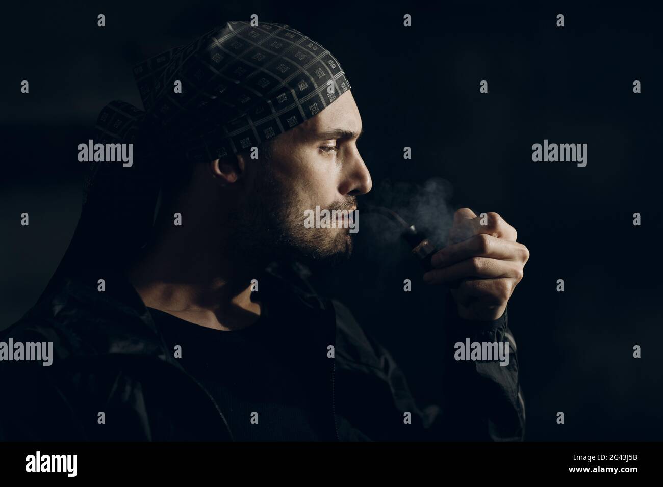 Man smoking a pipe on dark background. Back lit profile portrait Stock ...
