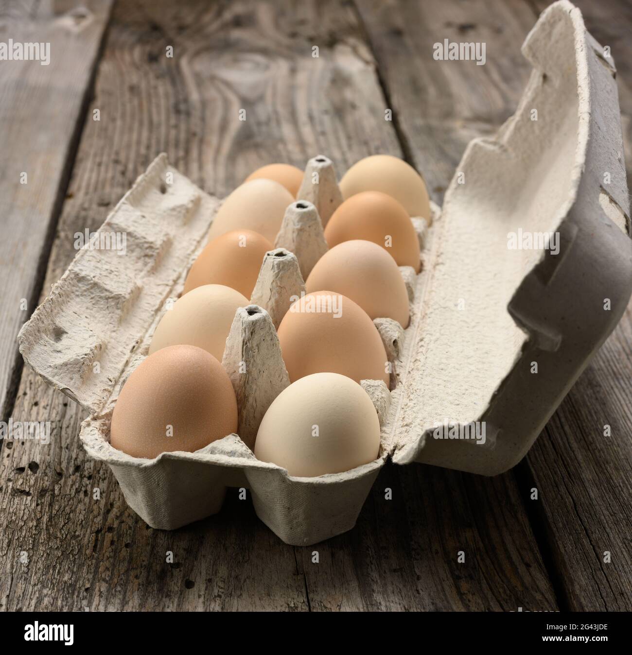 Fresh whole brown eggs in paper packaging on a gray wooden background ...