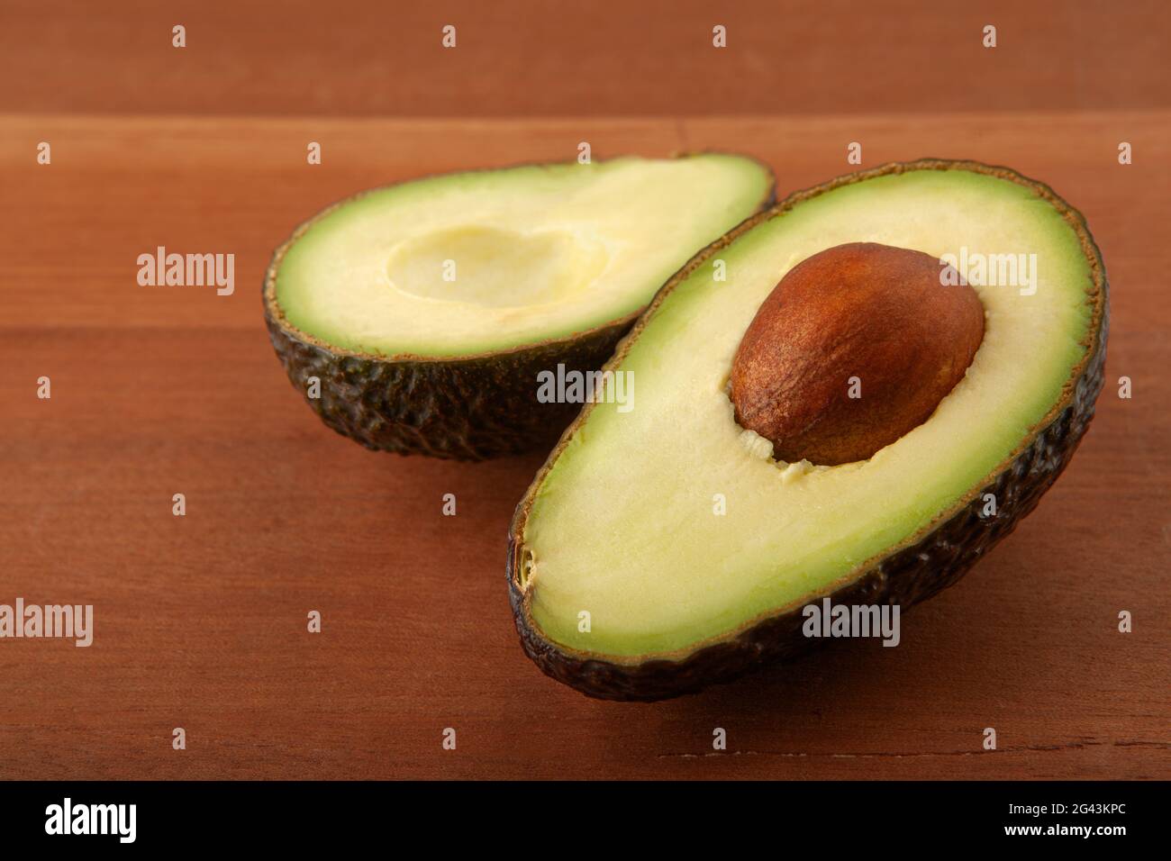 Closeup Avocado cut in half on wooden board background Stock Photo - Alamy