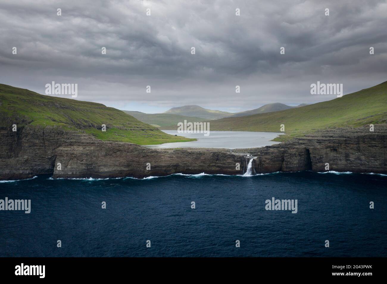 Coast, waterfall and cliffs at Trælanípa on the island of Vagar, on ...