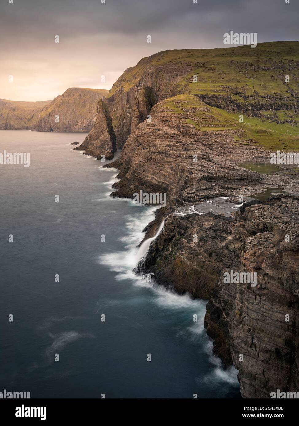 Coast, waterfall and cliffs at Trælanípa on the island of Vagar, on ...