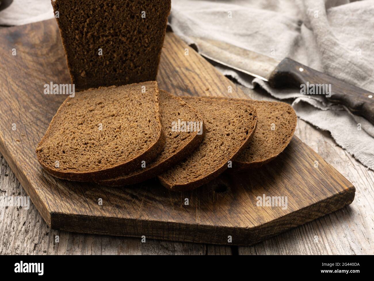 Sliced baked rectangular rye flour bread on brown board, healthy food ...