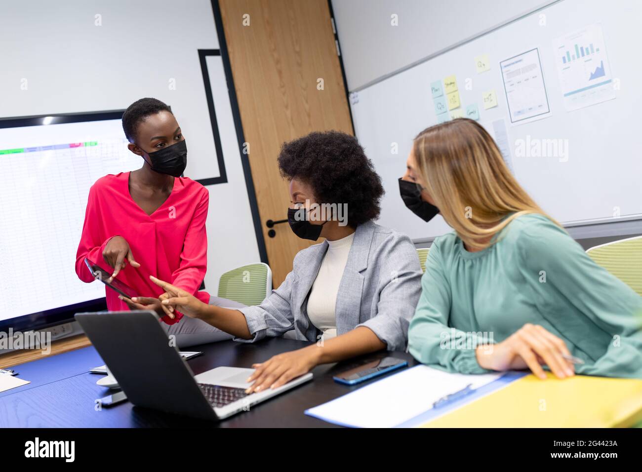 Diverse group of business colleagues wearing masks in discussion in ...