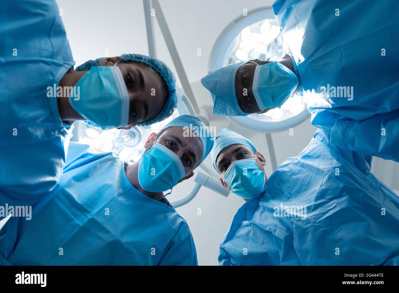 Diverse surgeons wearing face masks and protective clothing in ...