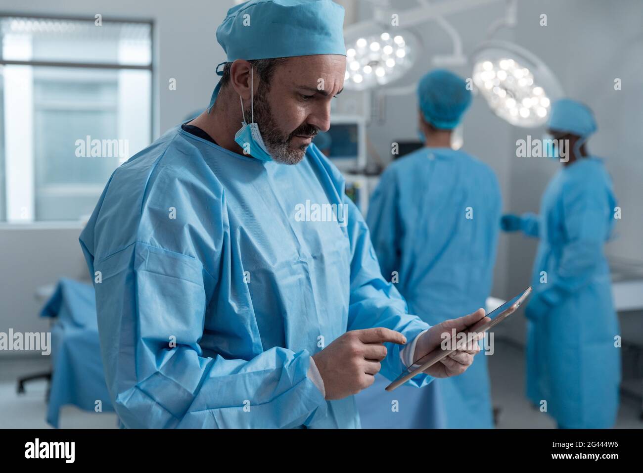Caucasian male surgeon with face mask and protective clothing using ...
