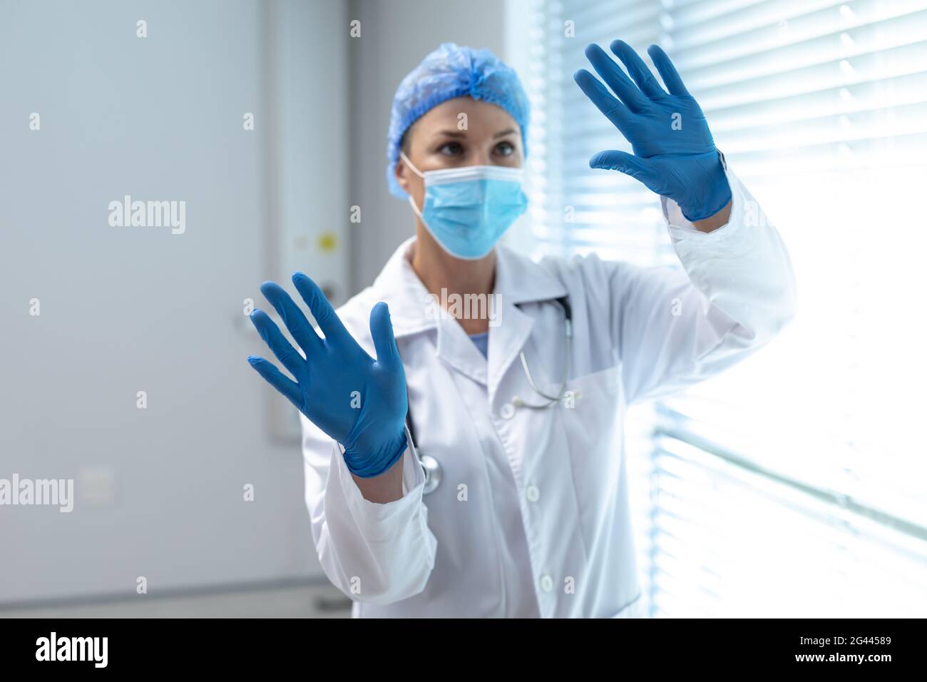 Caucasian female doctor wearing face mask using virtual interactive ...