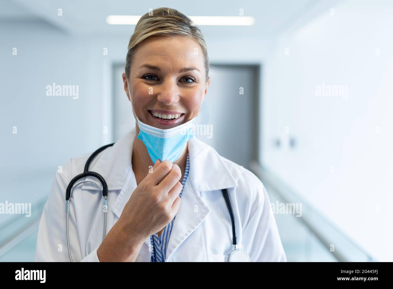 Portrait of happy caucasian female doctor wearing mask standing in ...