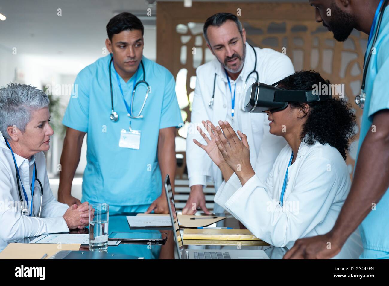 Diverse male and female doctors wearing face masks sitting at table and ...