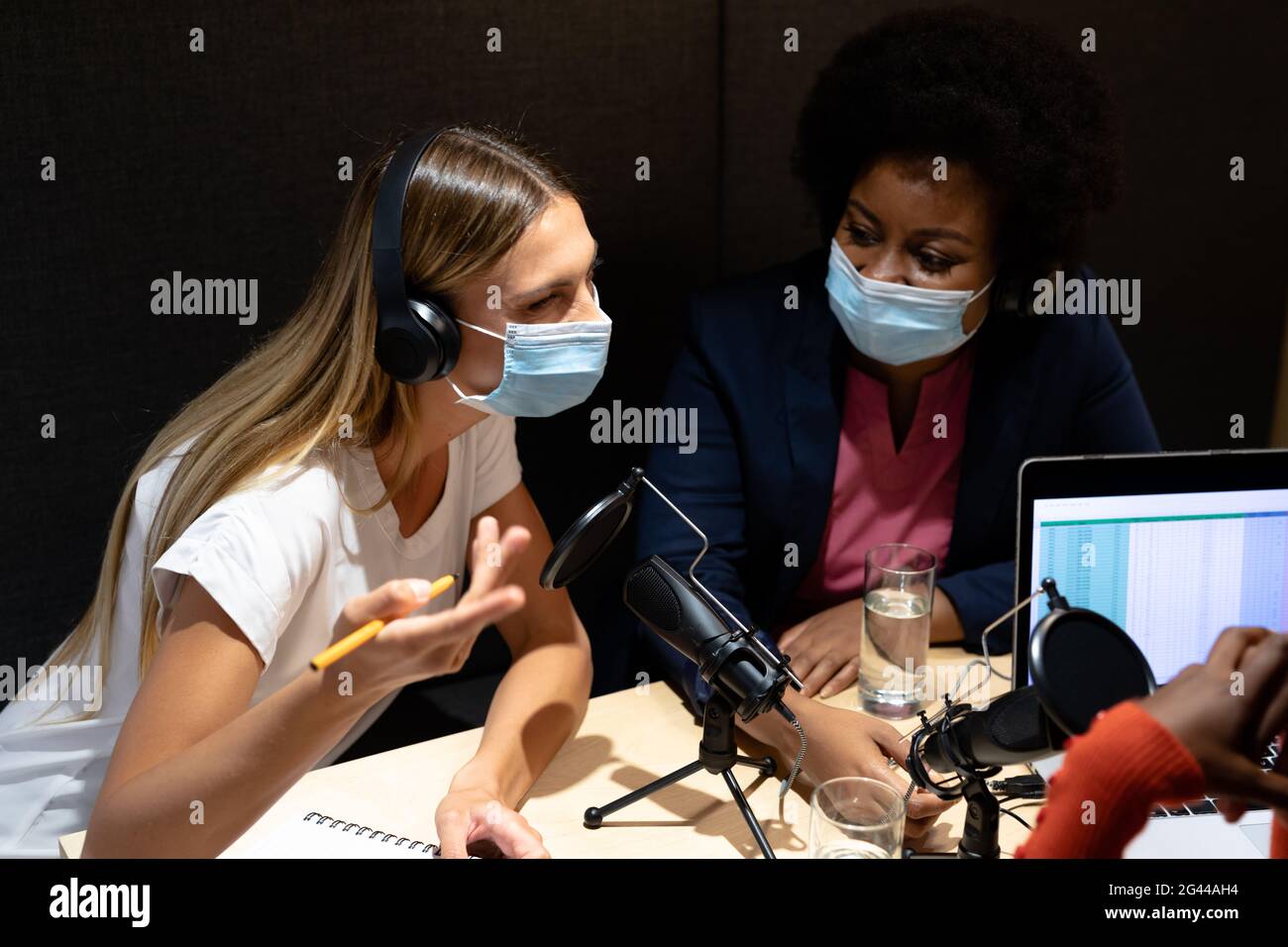 Diverse group of female business colleagues wearing masks in discussion ...