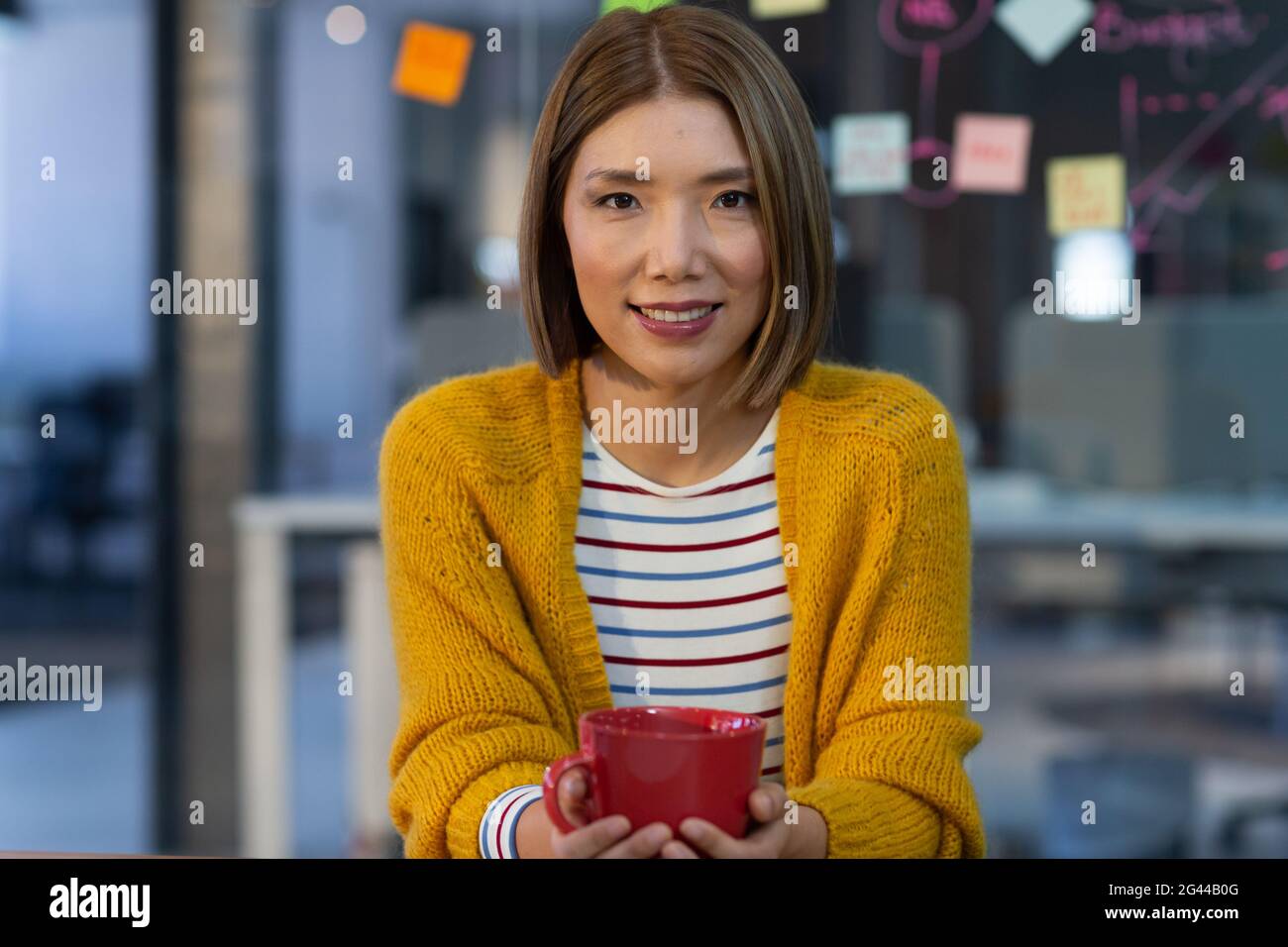 Portrait of asian businesswoman smiling and holding coffee mug sitting ...