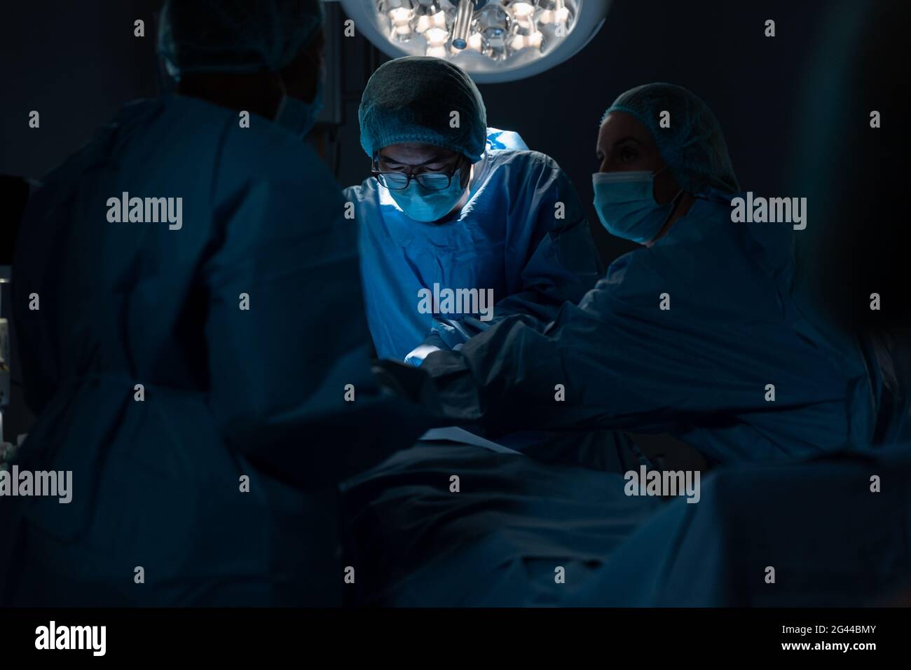 Diverse group of male and female surgeons in operating theatre wearing ...