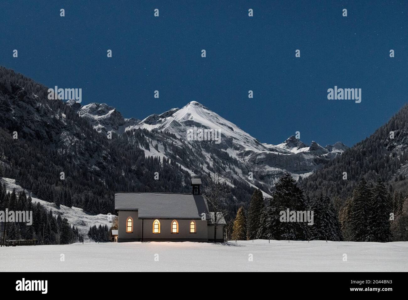 Church chapel in snowy winter landscape in front of mountain panorama ...