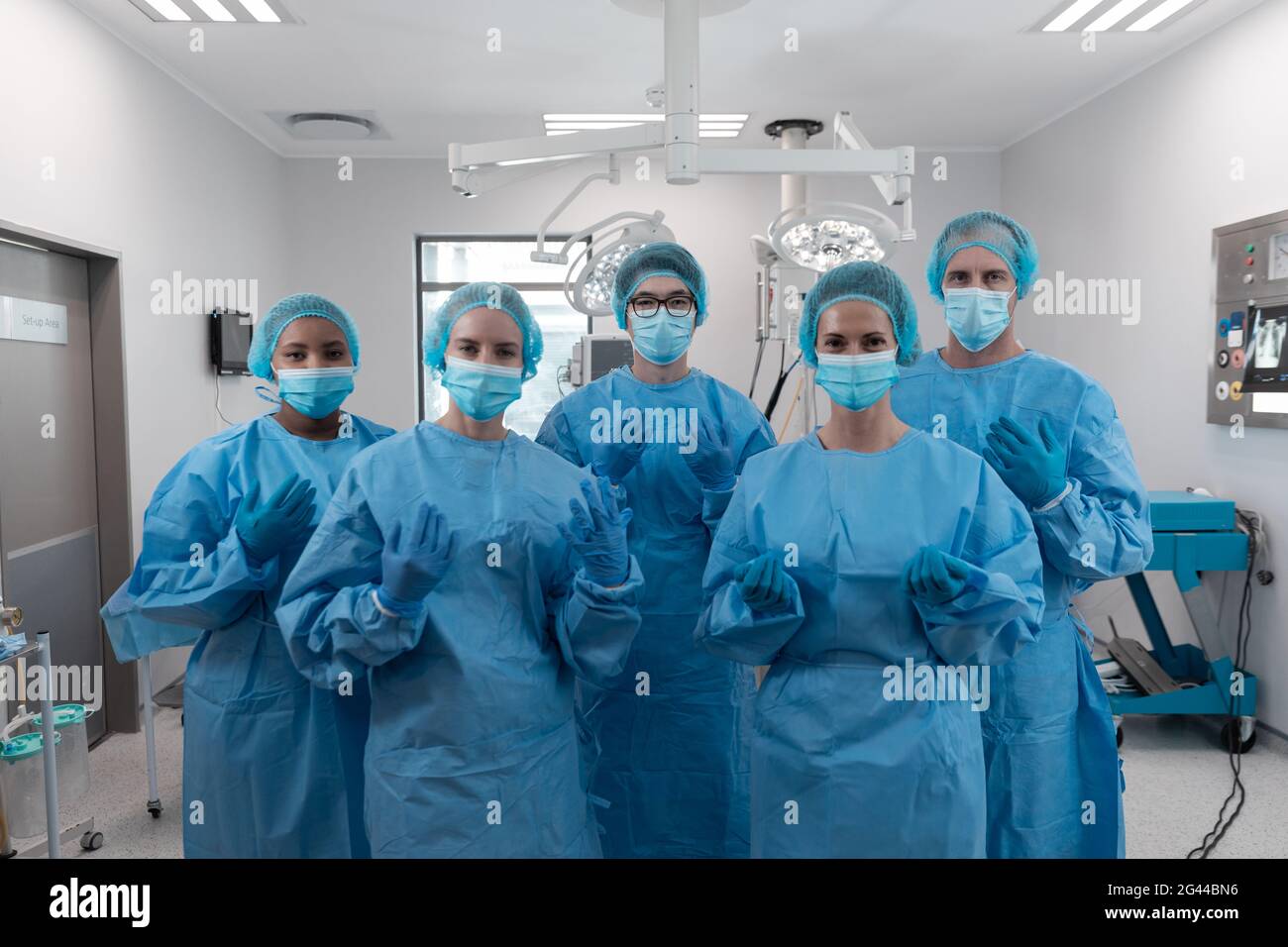 Diverse group of male and female surgeons standing in operating theatre ...