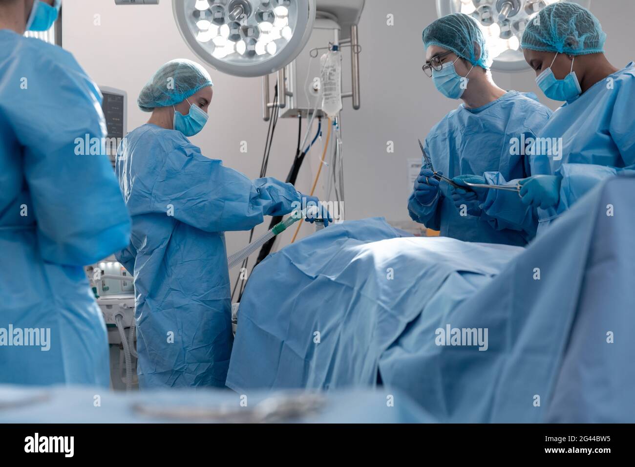 Diverse group of male and female surgeons in operating theatre wearing ...