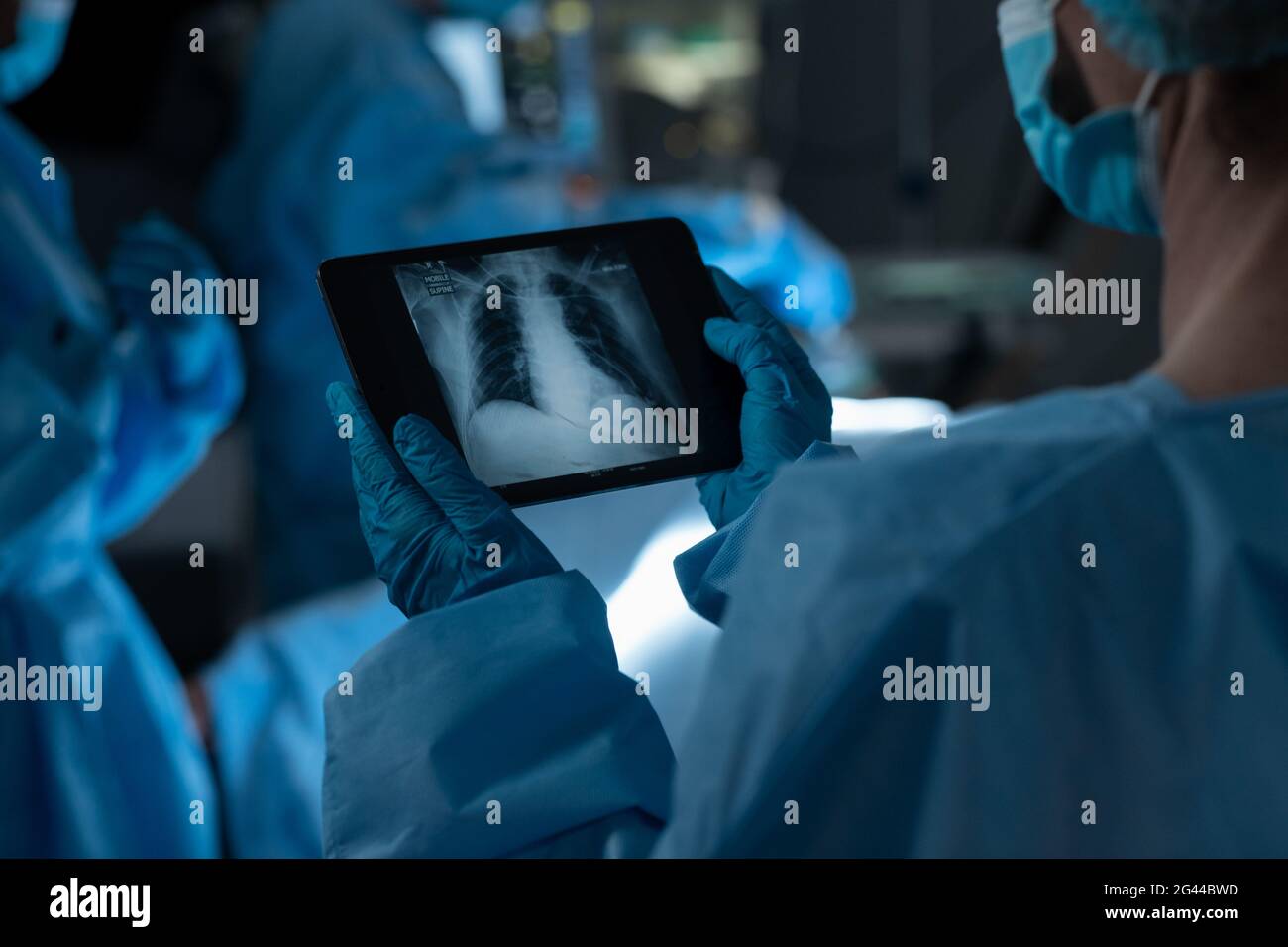 Mixed race surgeon in operating theatre wearing face masks looking at ...