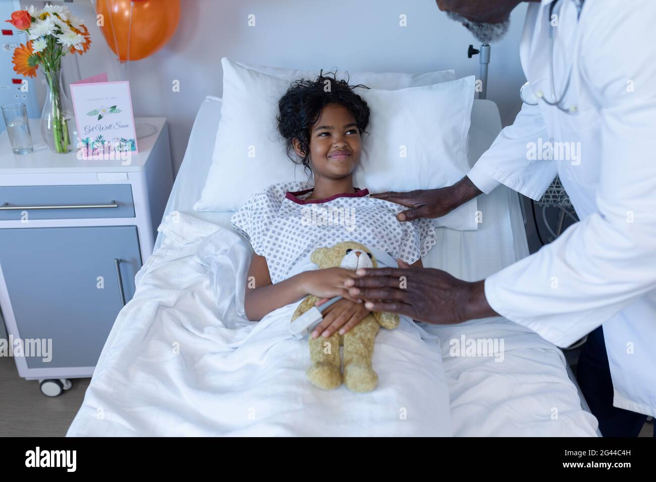 African american male doctor reassuring smiling sick mixed race girl in ...