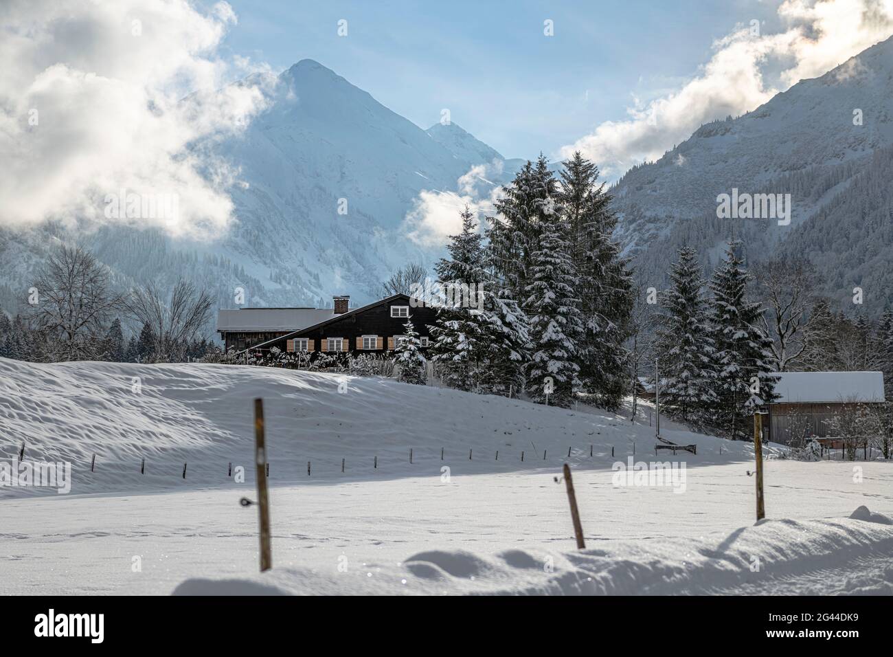 Farmhouse in snowy winter landscape in front of mountain panorama ...