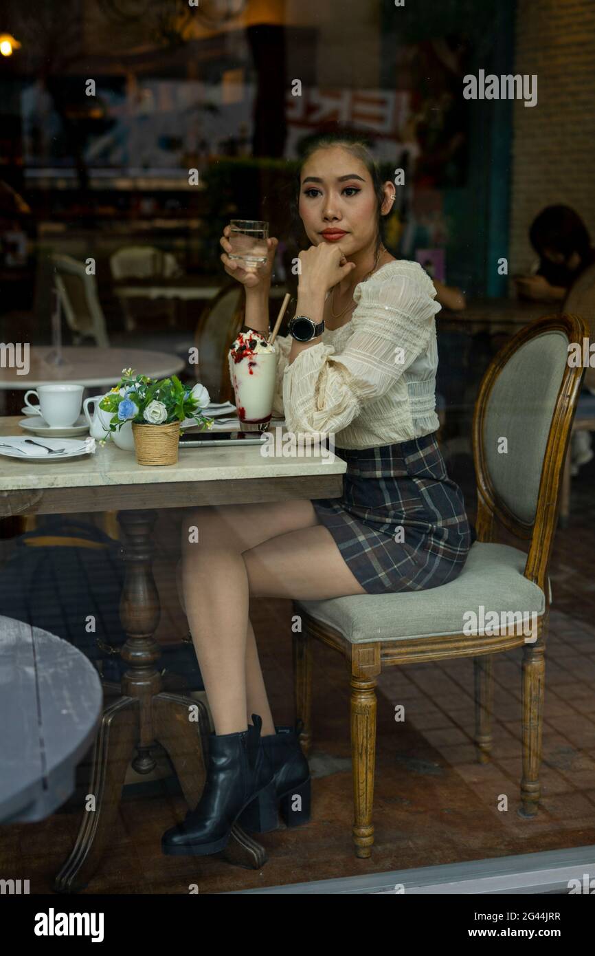 Very pretty dark hair asian girl posing in café window Stock Photo - Alamy