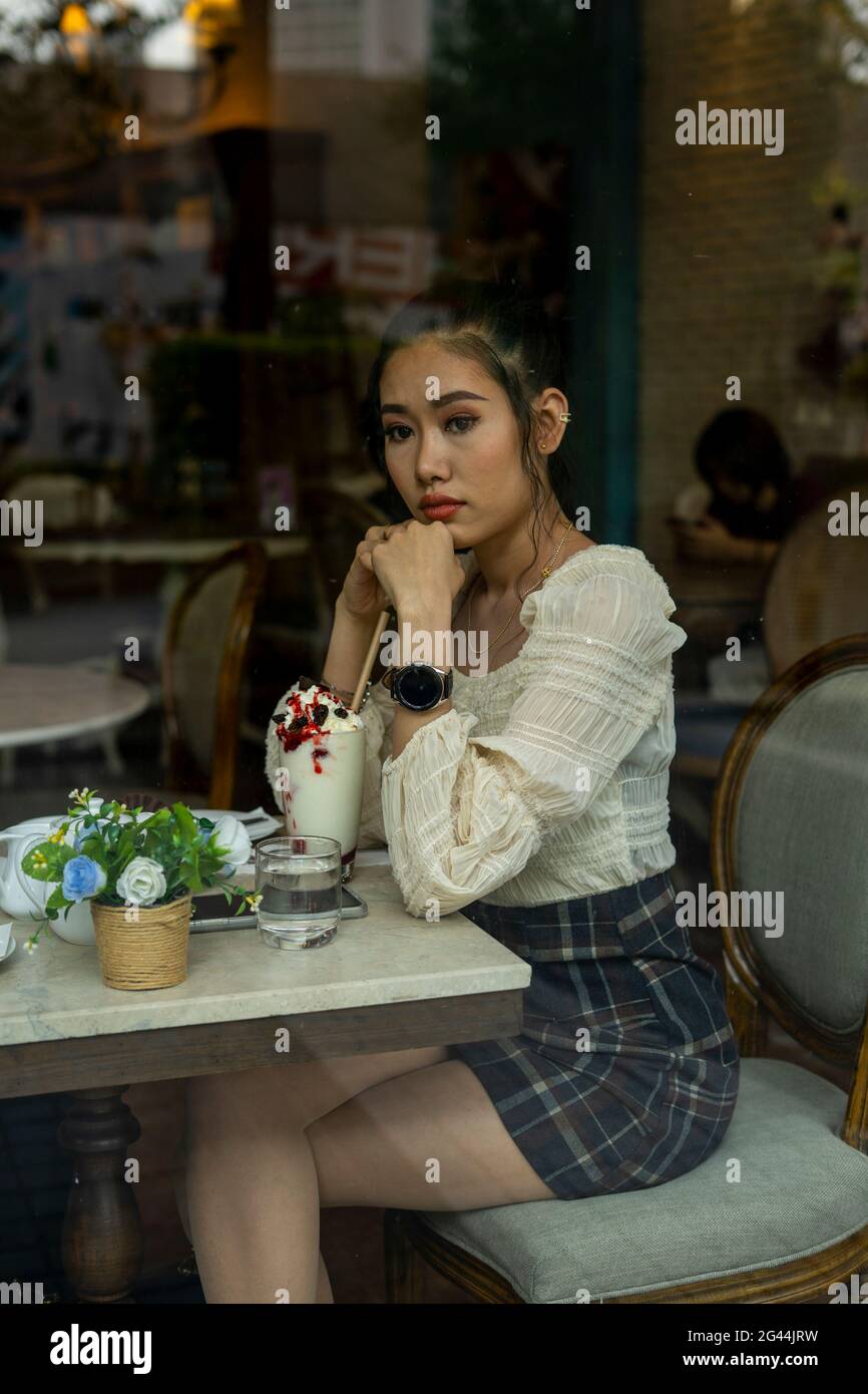 Very pretty dark hair asian girl posing in café window Stock Photo - Alamy