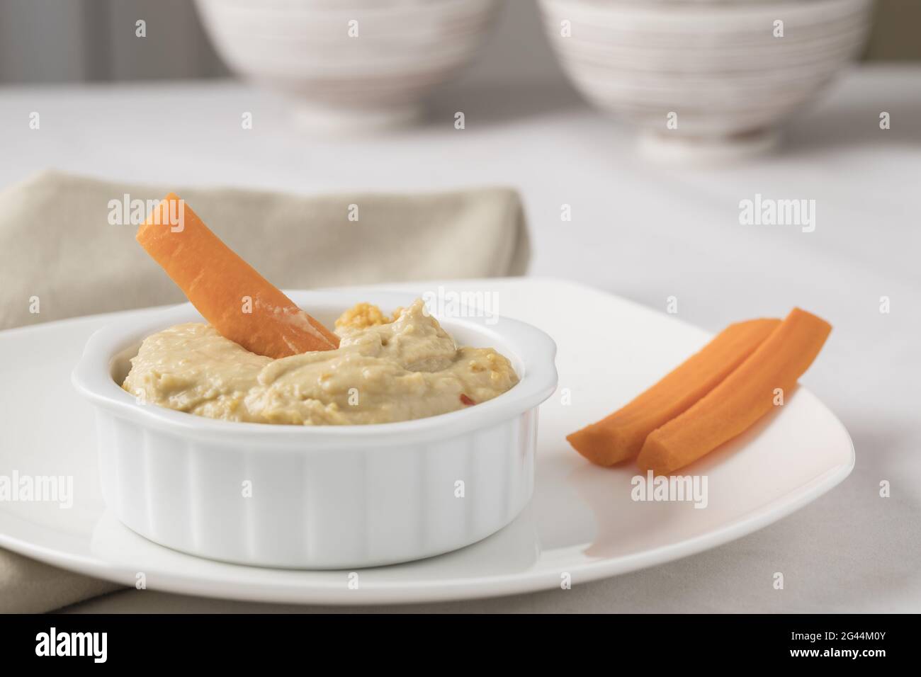 Carrot stick stands in bowl of hummus Stock Photo - Alamy