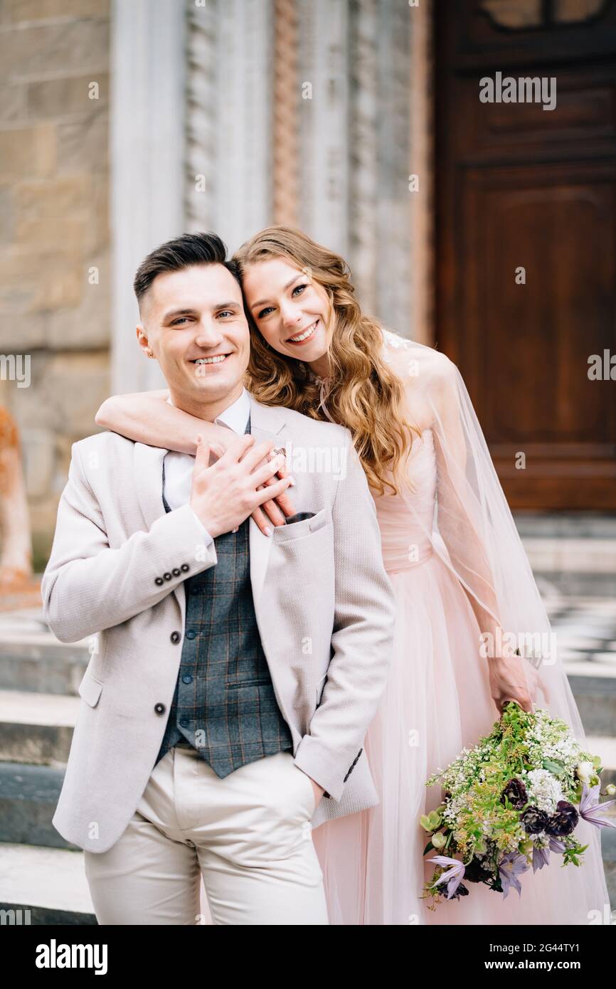 Smiling newlyweds hug on the steps at the entrance to the Basilica of ...