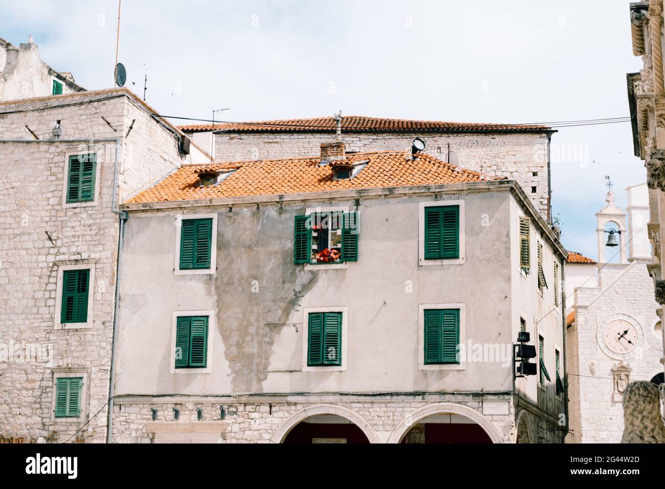 Old three-story residential building with green shutters and orange ...