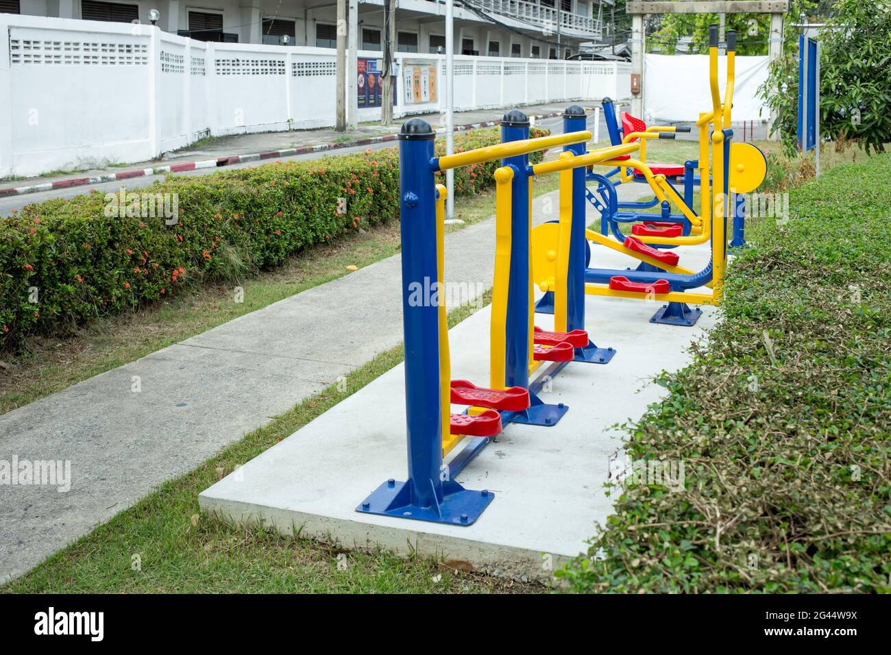 The yellow, red, blue exercise machine at the park next to the road ...