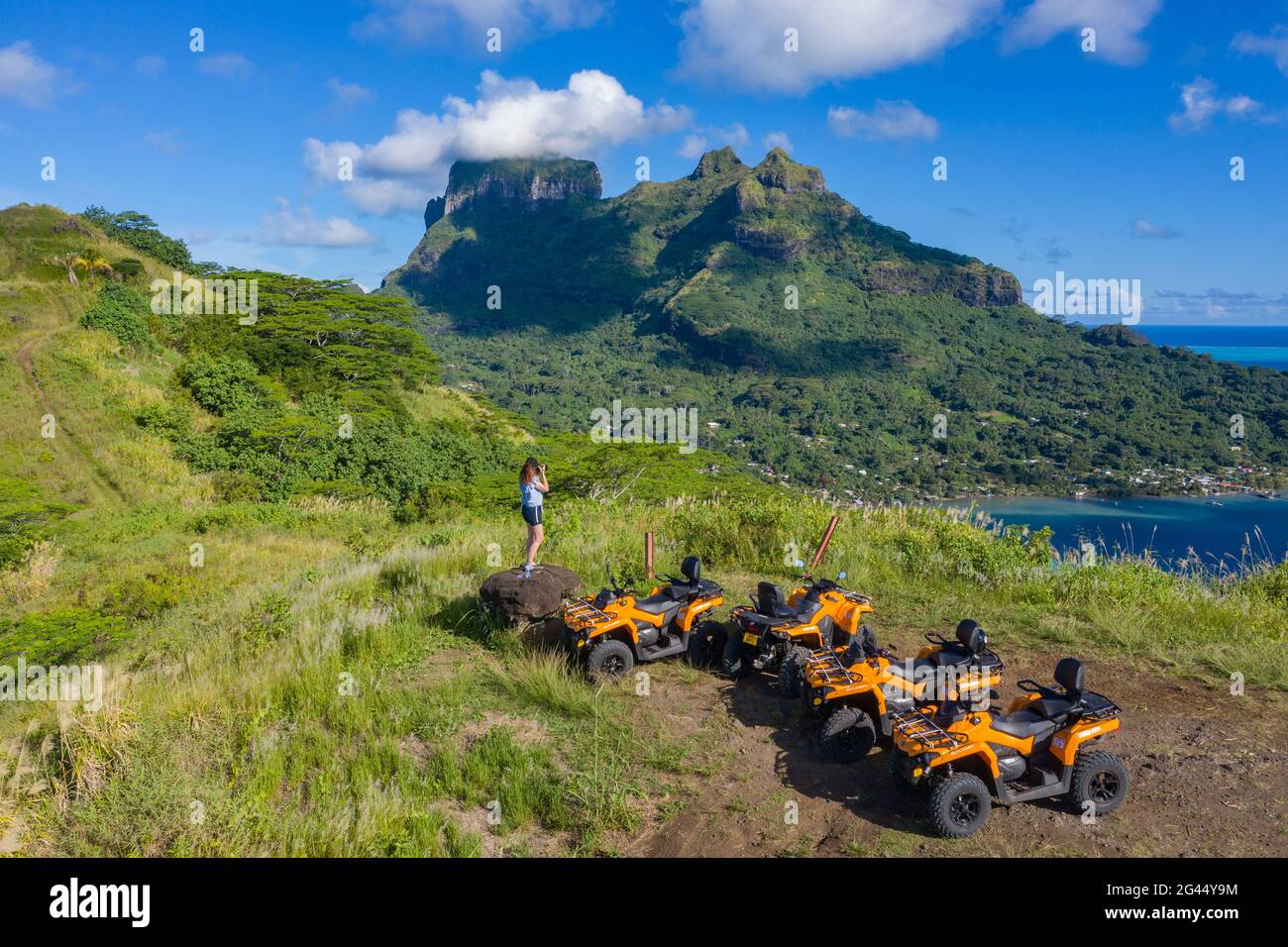 Aerial view of quad ATVs on hill with Mount Otemanu behind, Bora Bora ...