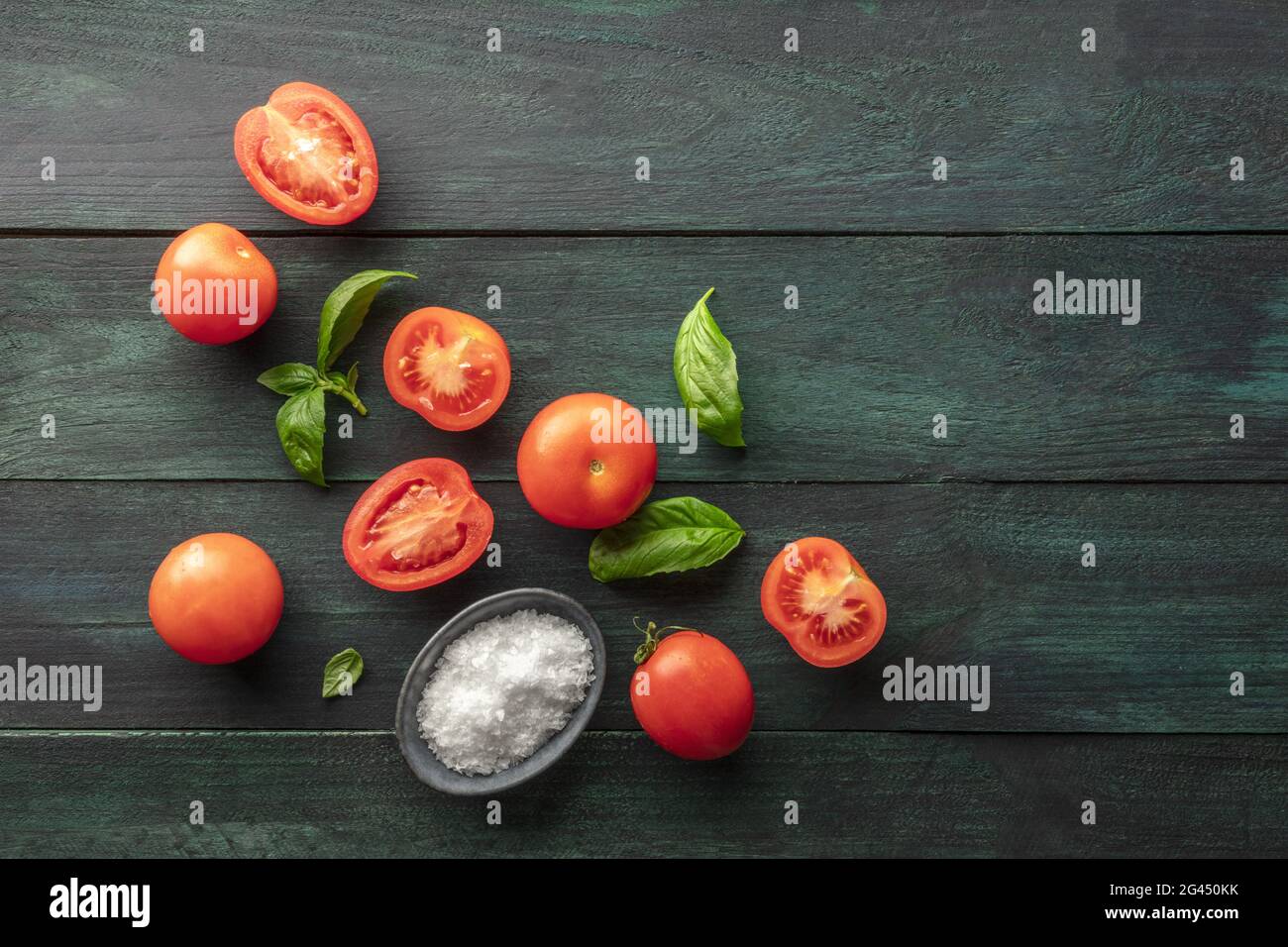 Organic heirloom tomatoes with fresh basil leaves, shot from above on a ...