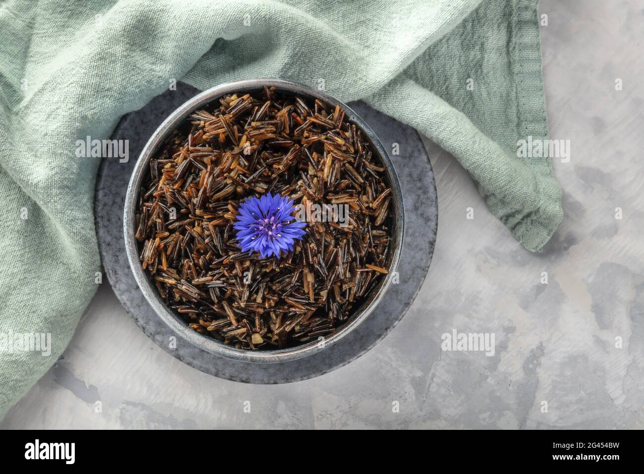 Wild black rice with an edible flower, a blue cornflower, shot from the ...