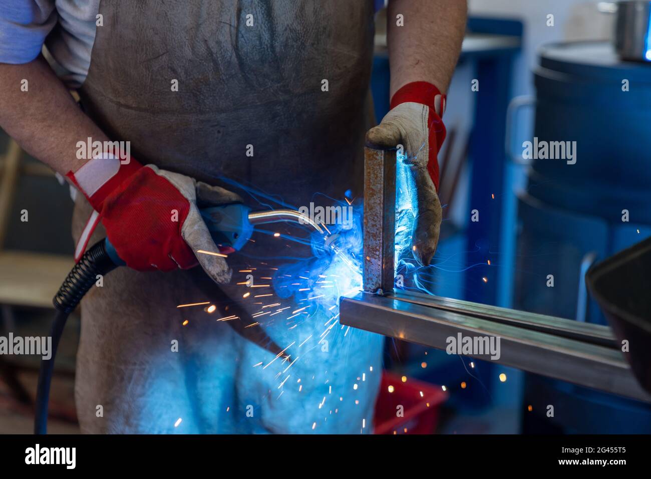 Detail of a man welding steel frames in a forgery and metal works ...