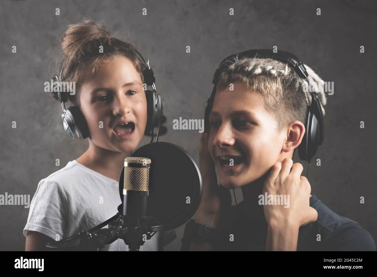Positive brother and sister are recording a song in the studio. Young ...