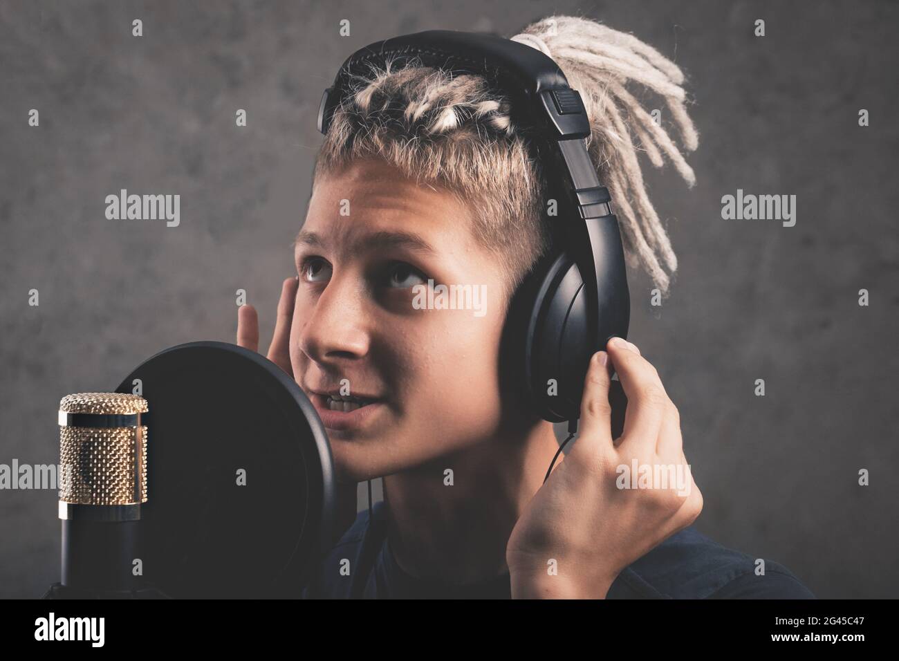 Happy positive guy with dreadlocks is recording a song in the studio. A ...