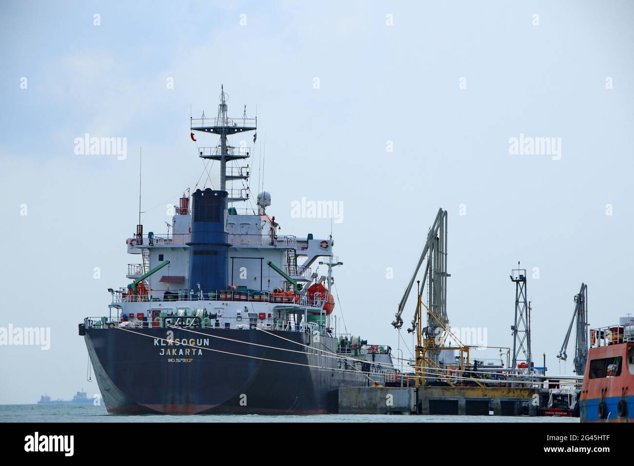 Large cargo ship loading in port terminal, cranes in the background ...