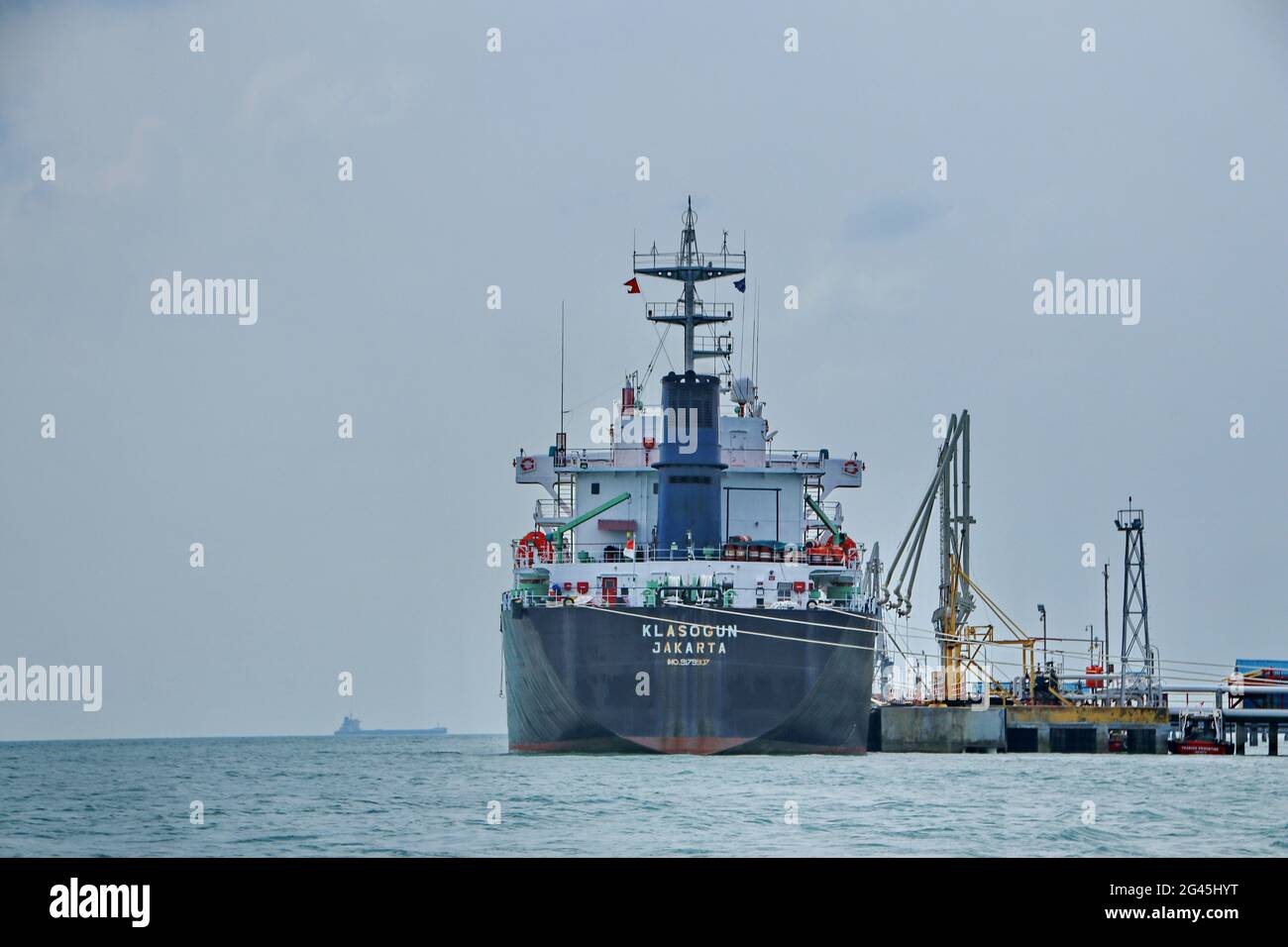 Large cargo ship loading in port terminal, cranes in the background ...