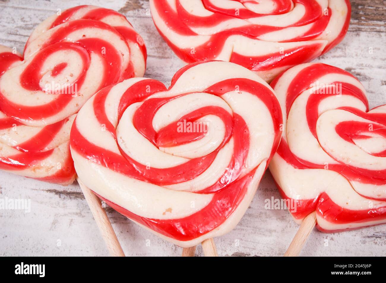 Sweet colorful funny lollipop in shape of heart on old rustic board ...