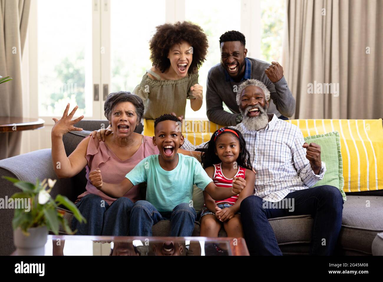 Multi generation mixed race family spending time together watching game ...
